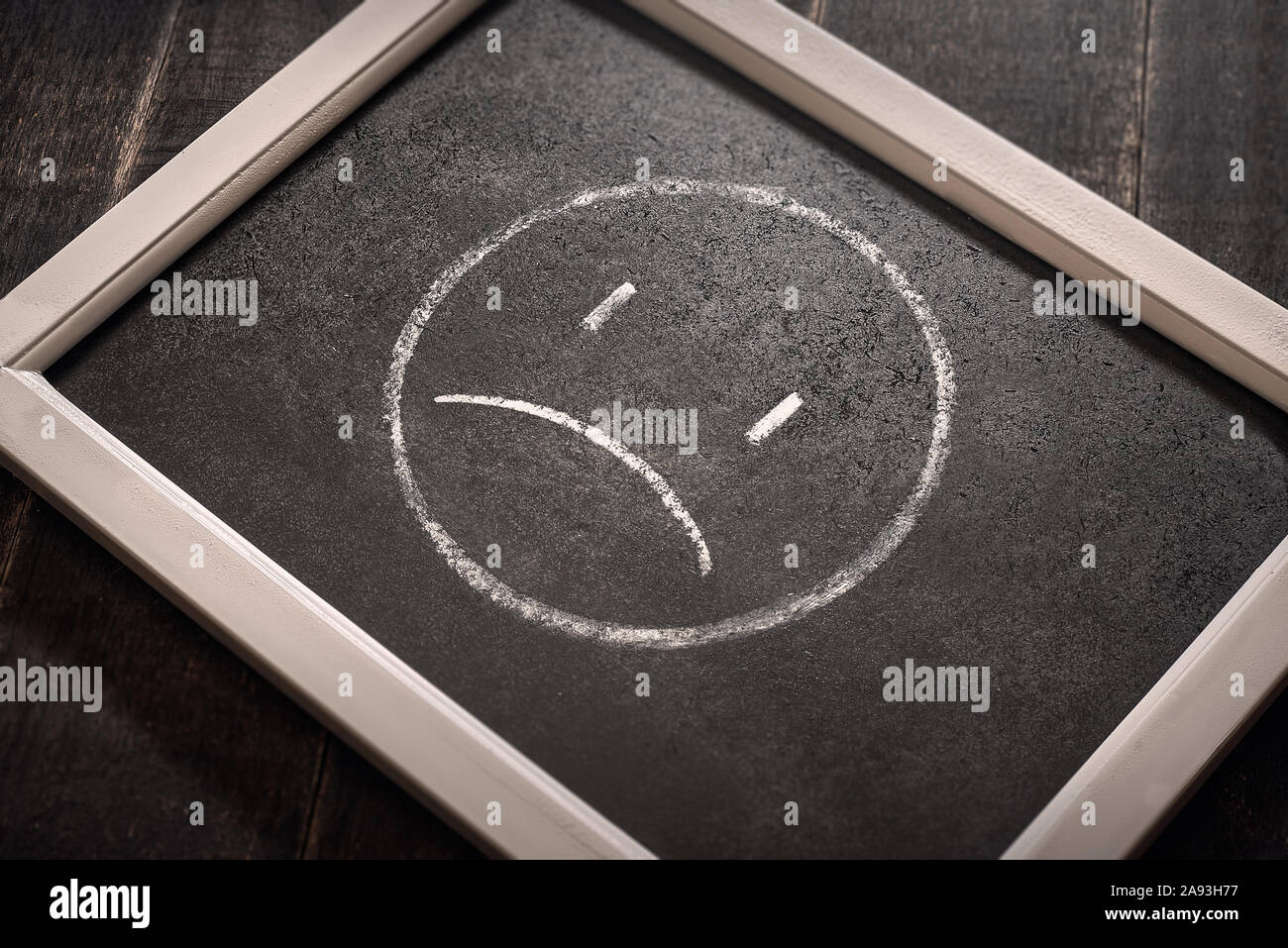 Hand drawing sad smiley face on black chalk board. Negative human ...