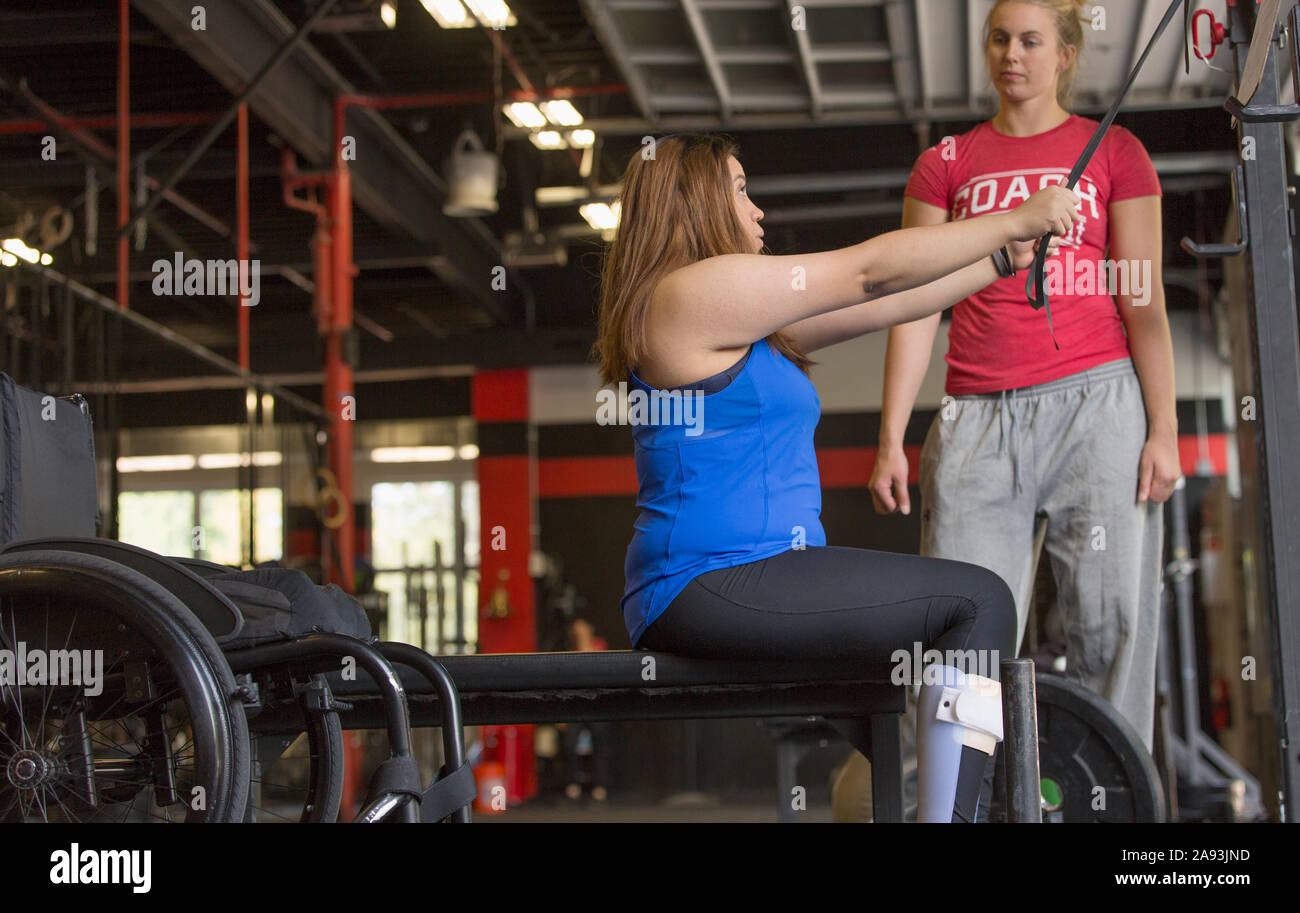 Woman with spinal cord injury working out in a gym with a trainer Stock ...