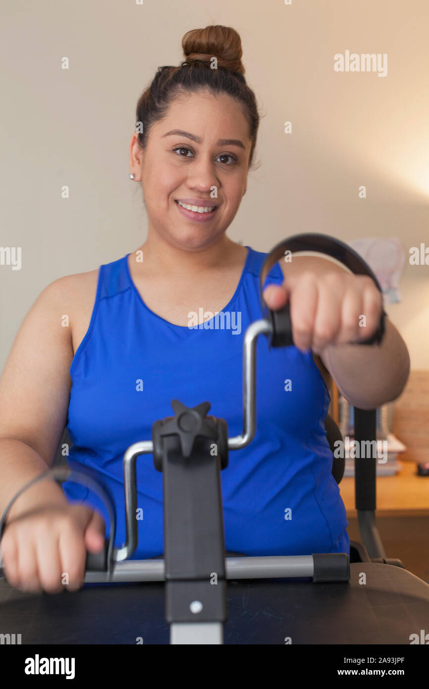 Latina woman with spinal cord injury getting into her desk so she can ...