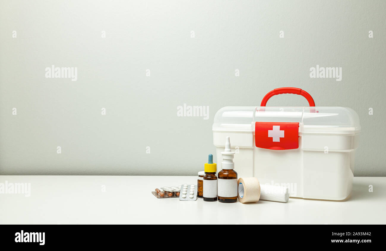 First Aid Kit. White box with a cross and a red fastener and pills with ...