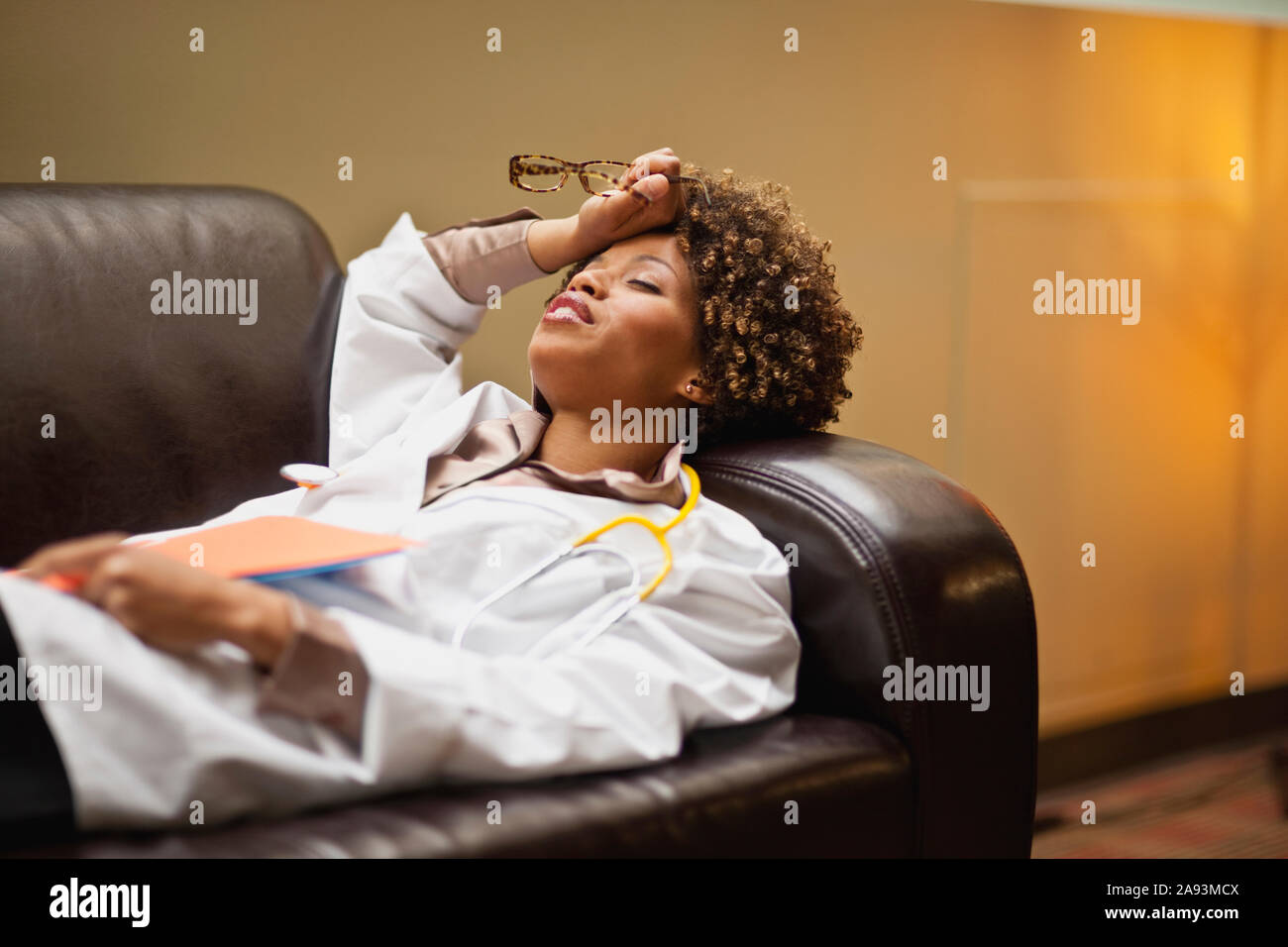 Female doctor taking a nap on a sofa Stock Photo - Alamy