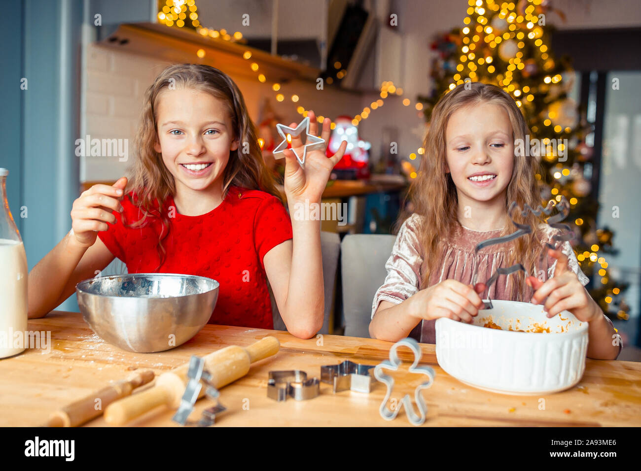 Adorable little girls baking cookies background of lights and Christmas ...