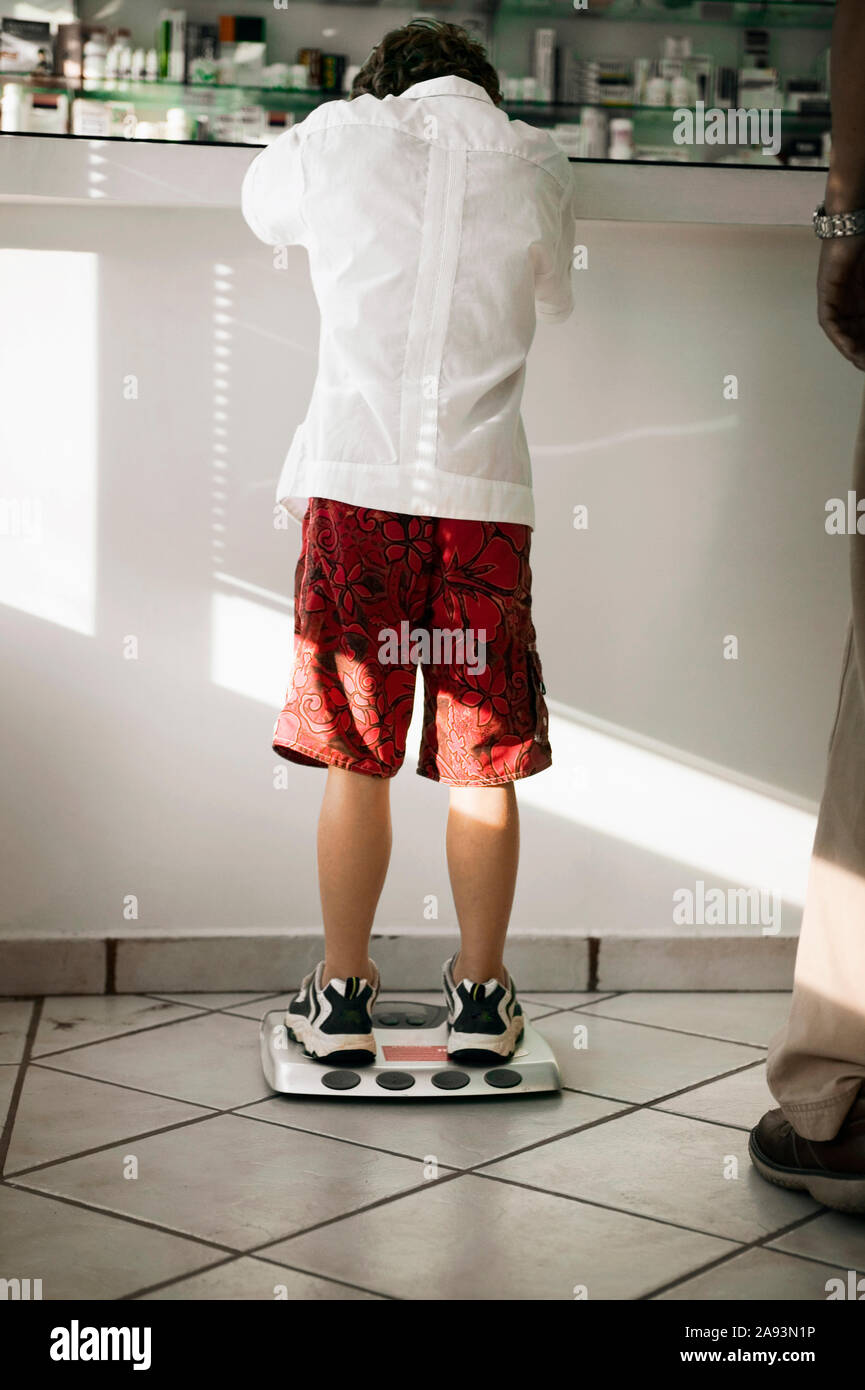 Rear view of a small boy checking his weight through the scale Stock ...