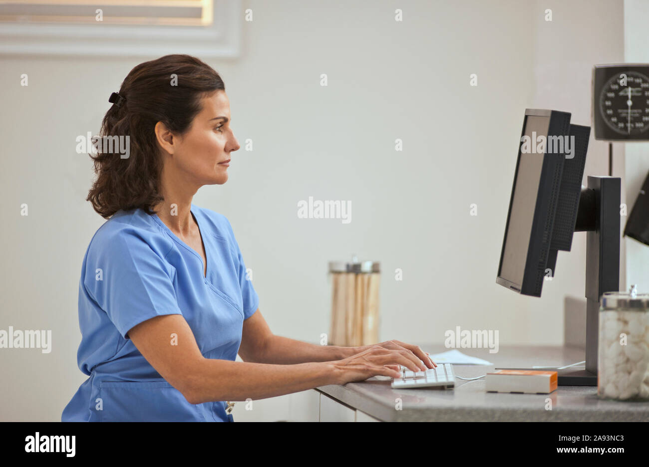 Contemplative nurse using a computer inside an office Stock Photo - Alamy