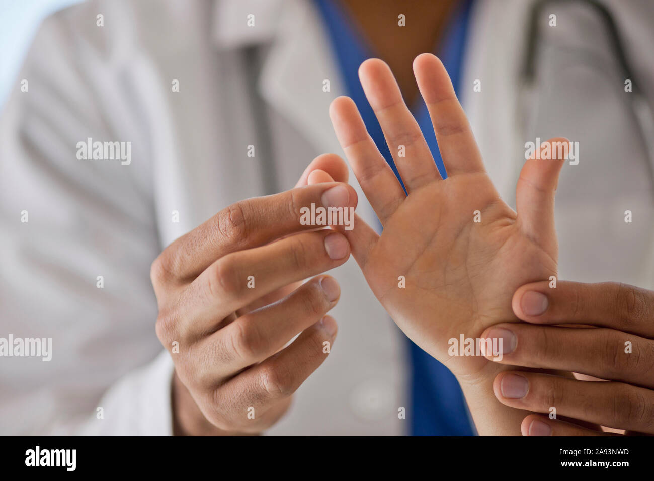 Doctor examining the hands of a young patient Stock Photo - Alamy