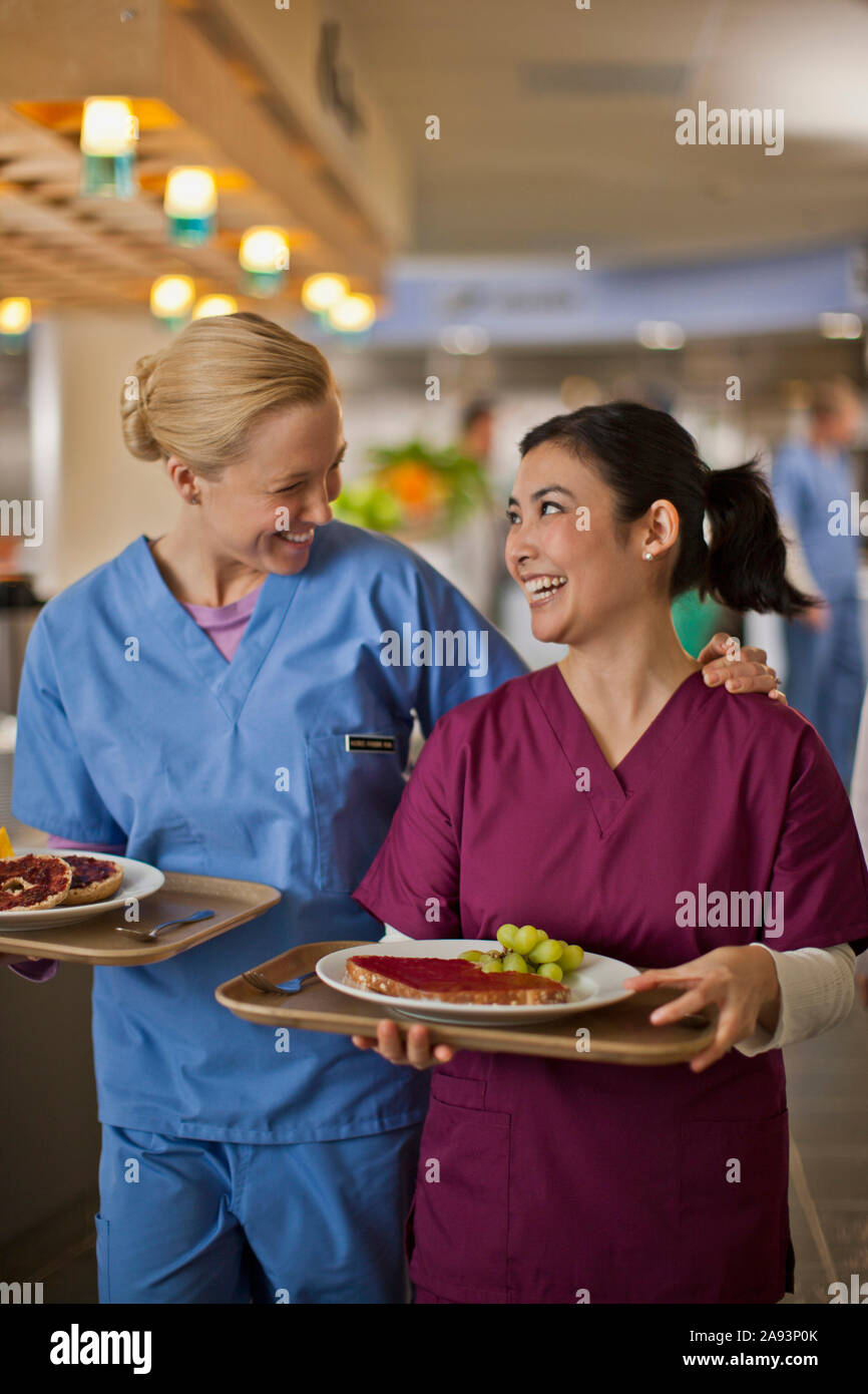 Two young nurses smile and chat together as they get their lunch from ...