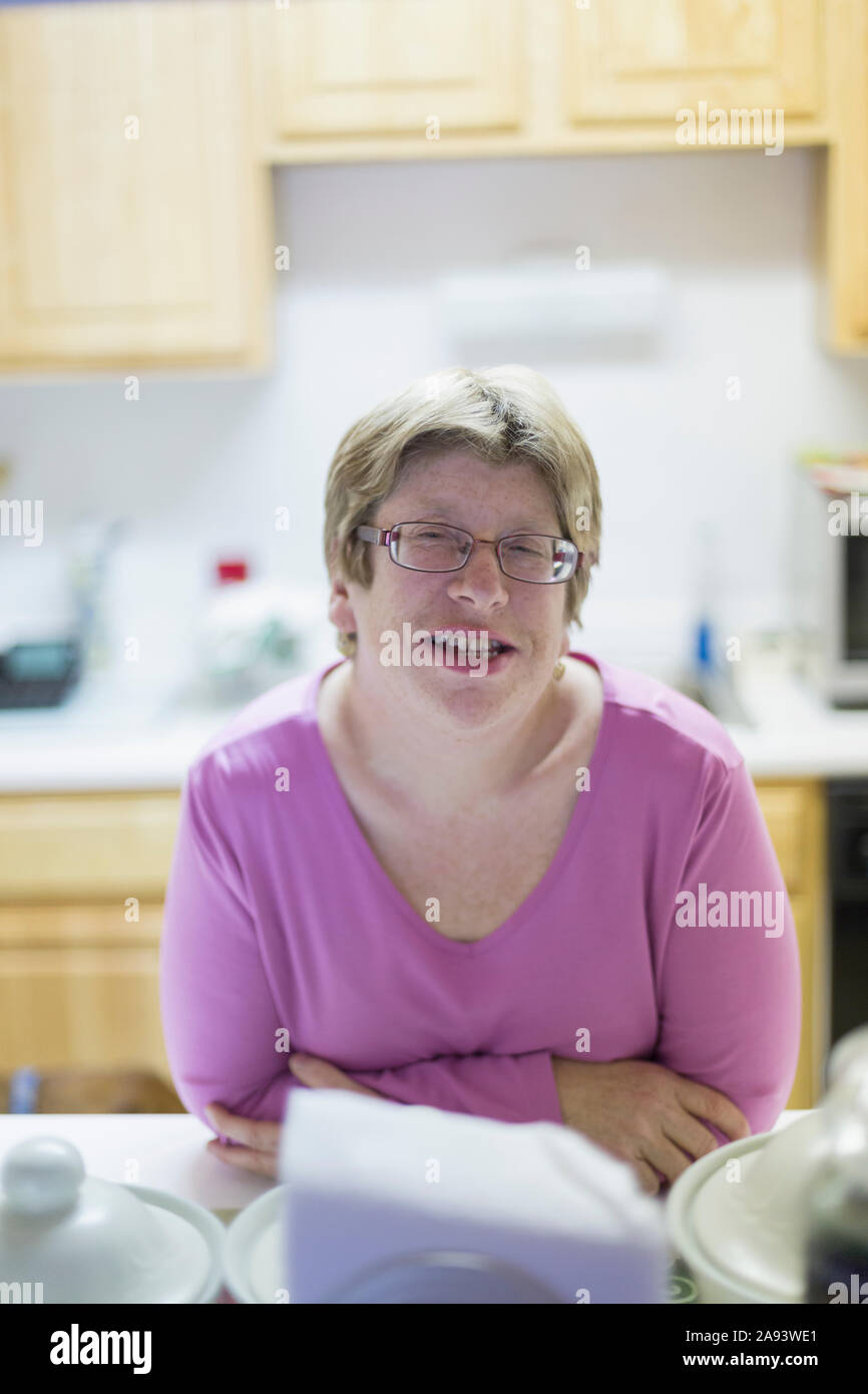 Woman with Autism smiling at dining table Stock Photo - Alamy
