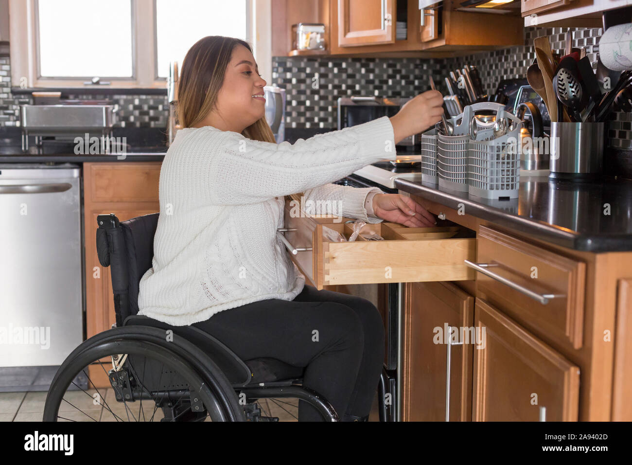 Woman with Spinal Cord Injury arranging dishwasher Stock Photo - Alamy
