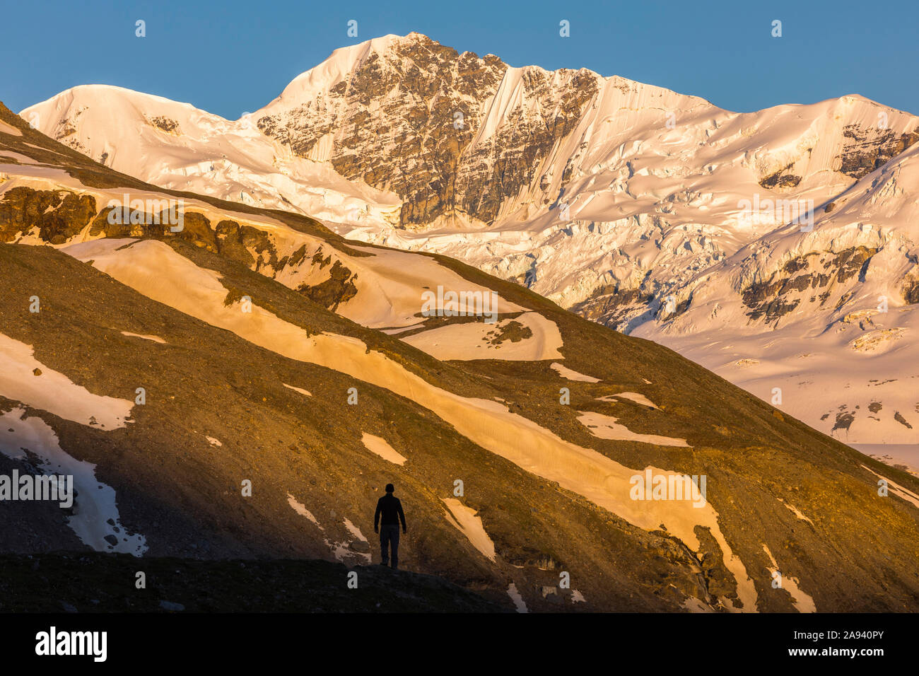 A man stands silhouetted in front of M'Ladies Mountain at sunset in the ...
