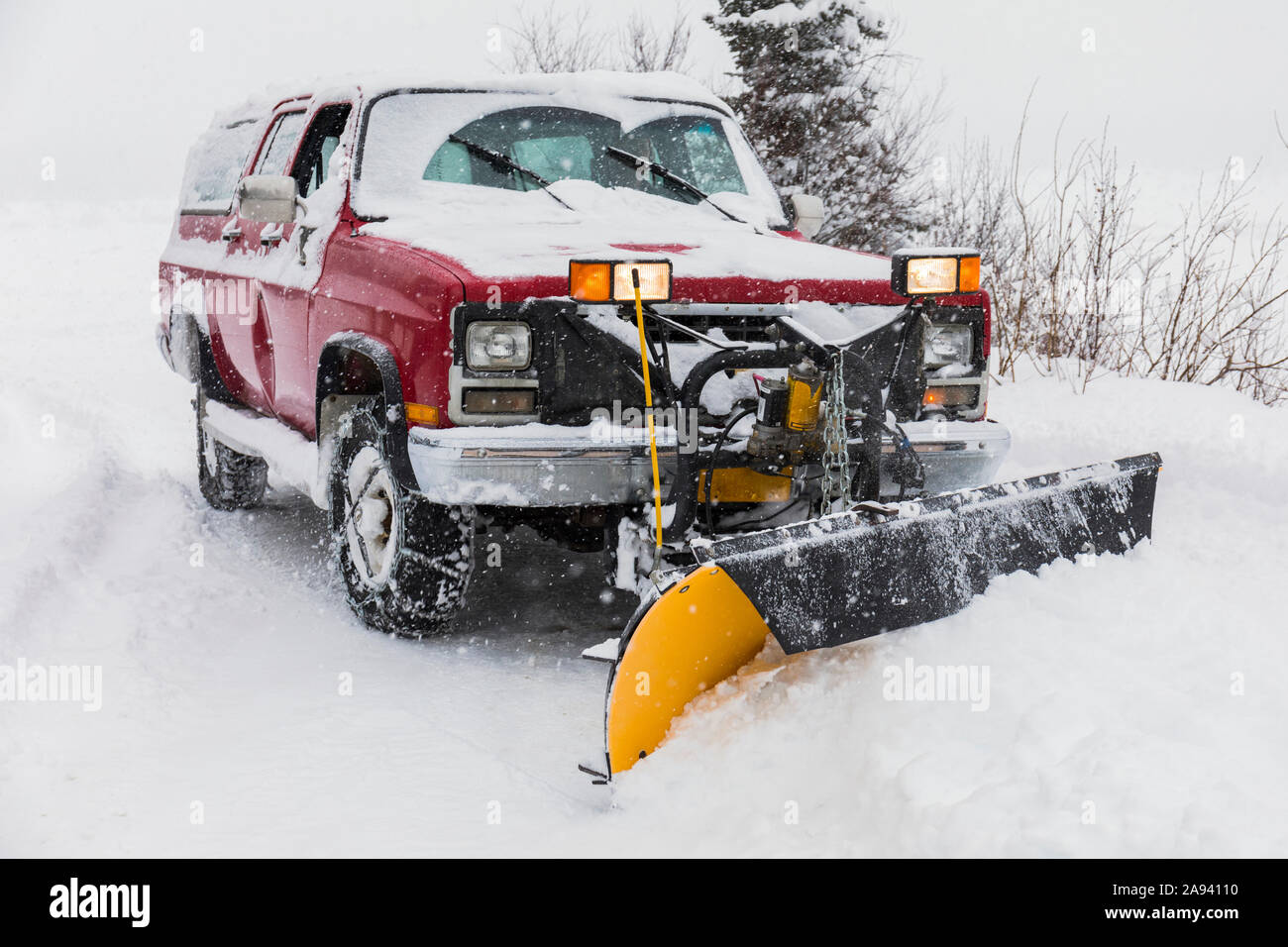 A truck with a plow clears snow from a driveway during blizzard ...