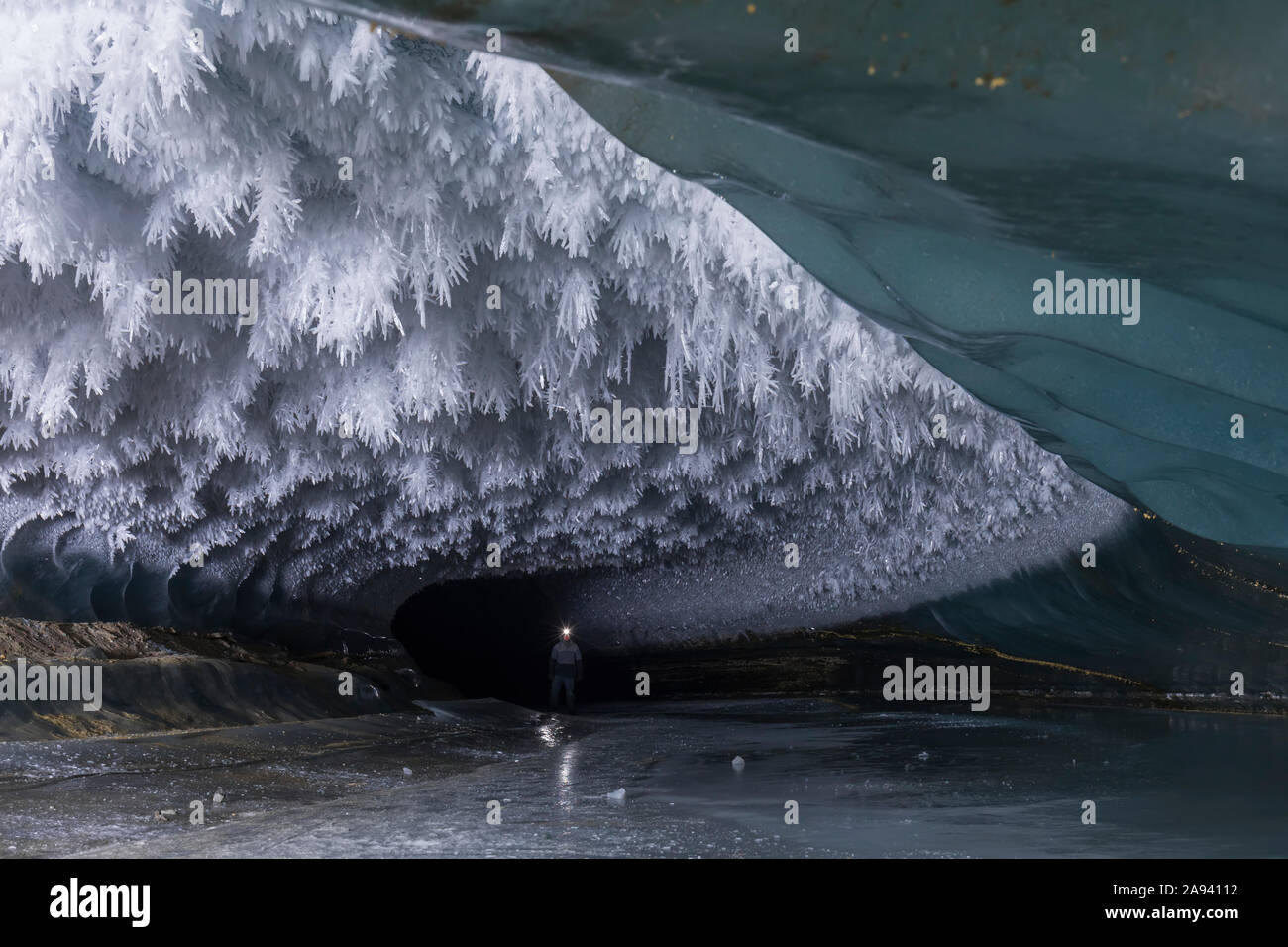 A man with a headlamp explores a Castner Glacier ice cave with ...