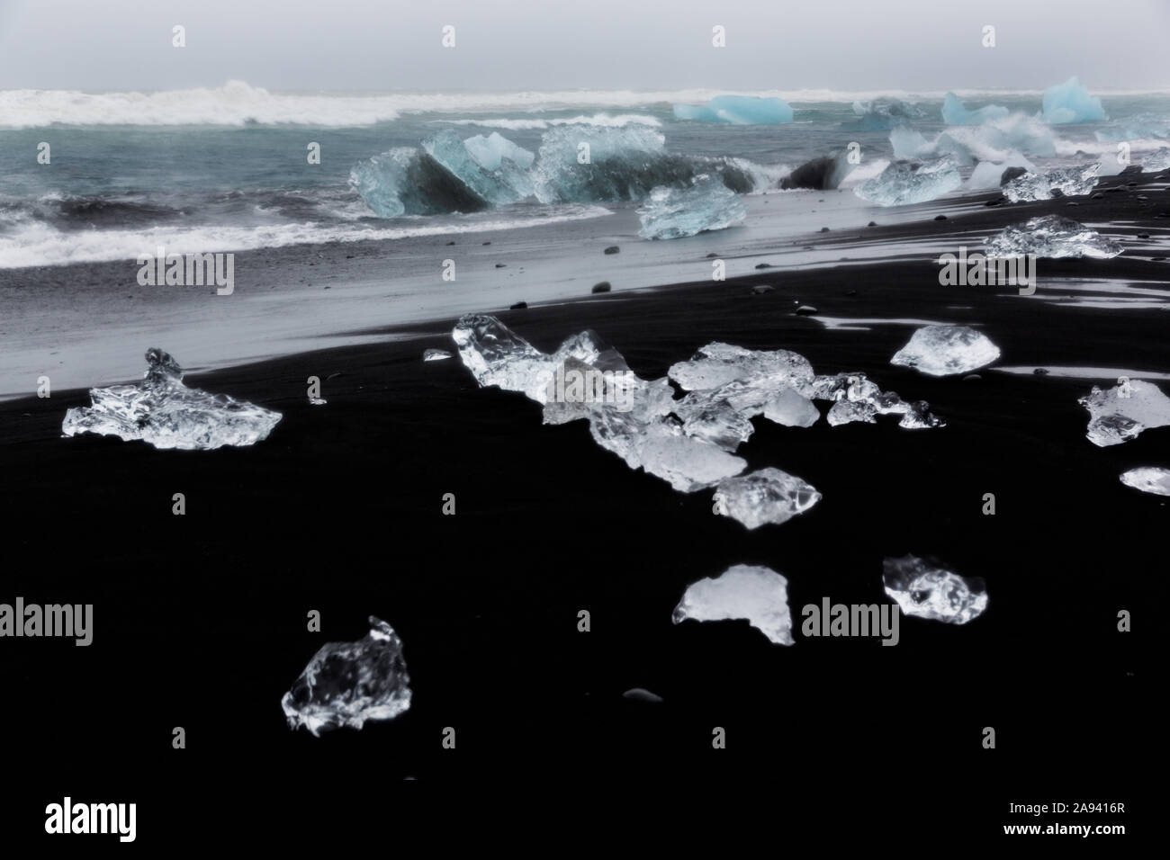 Glistening chunks of ice wash up on a lava black sand beach in the ...