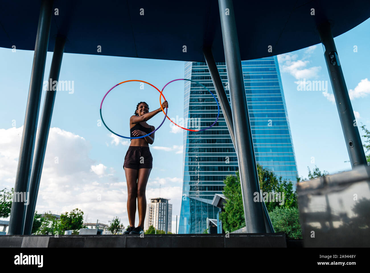 Mixed race generation Z woman performing Hula Hoop dance in downtown ...