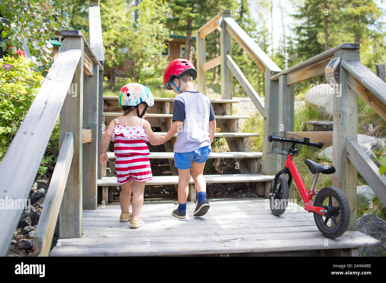 Brother holding hands with sister helping her up wooden stairs Stock ...