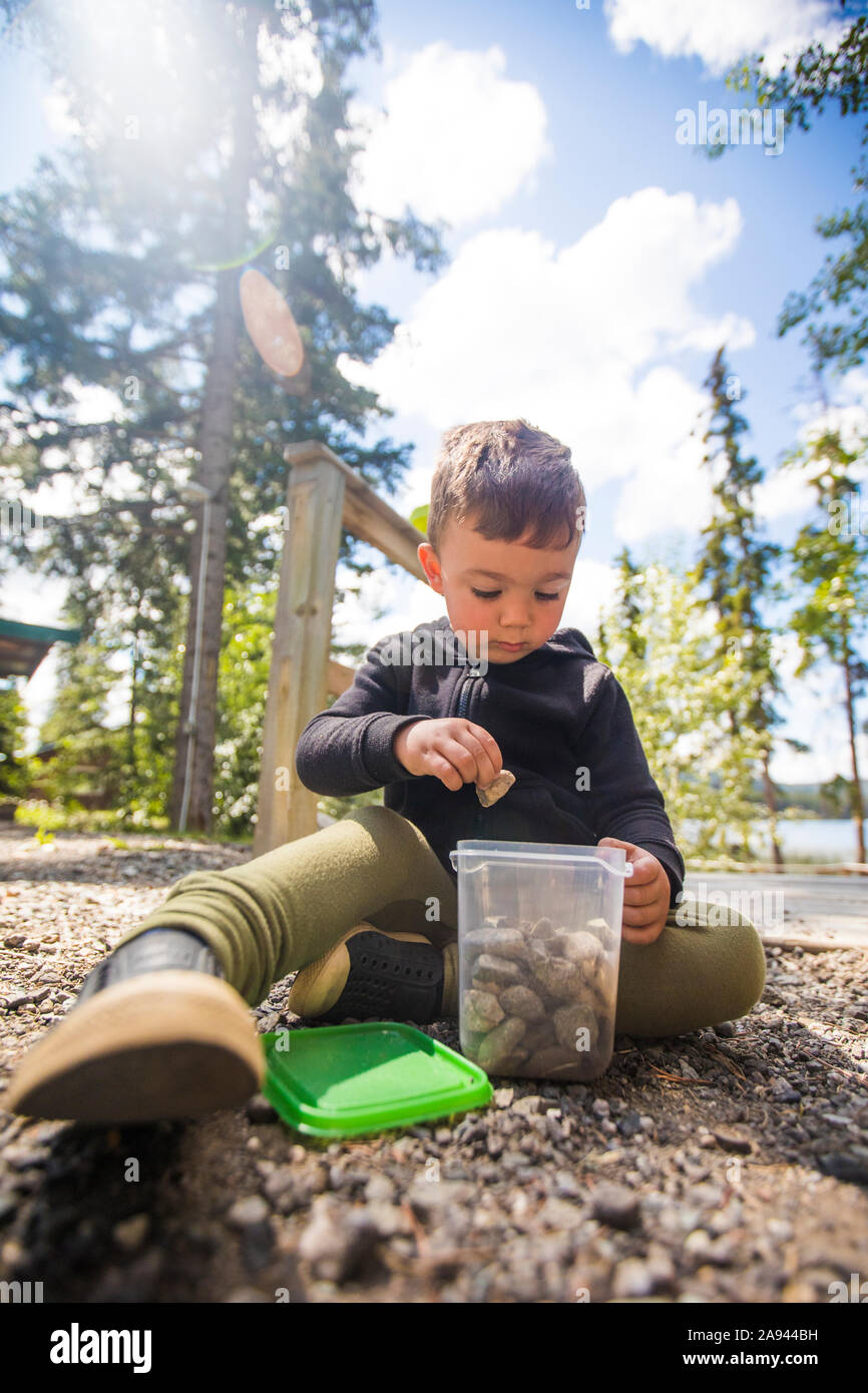 Young boy collects rocks in clear container outdoors Stock Photo - Alamy