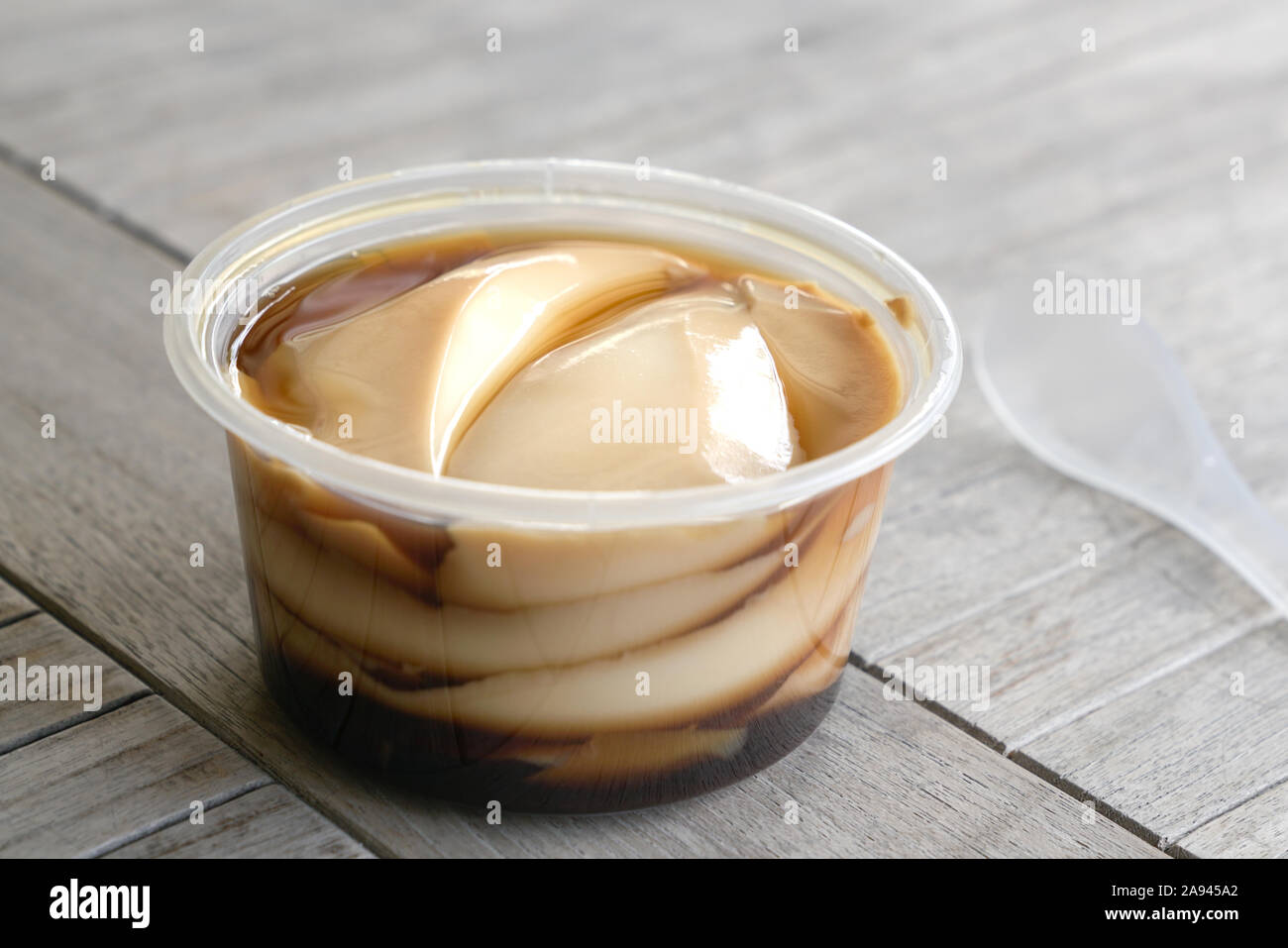 Soybean pudding (Taufufa) with brown sugar syrup in a plastic container ...
