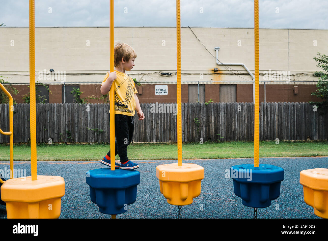 A little boy walks across a play structure Stock Photo - Alamy
