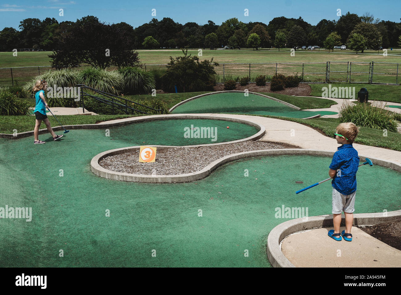 Two children play mini golf Stock Photo - Alamy