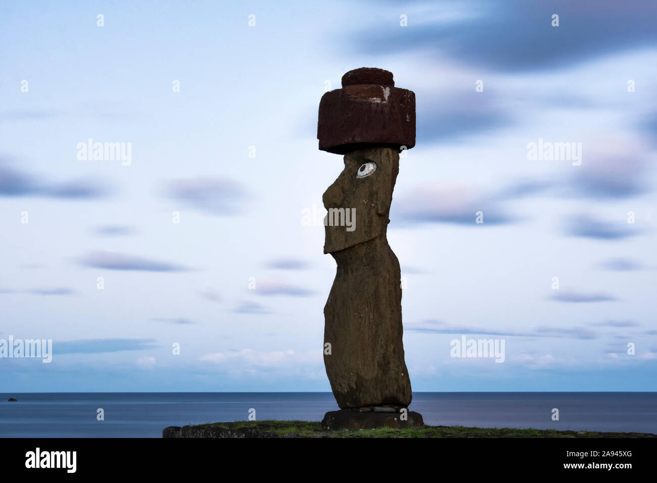 A single moai on a blue background of sky, clouds and ocean; Easter ...