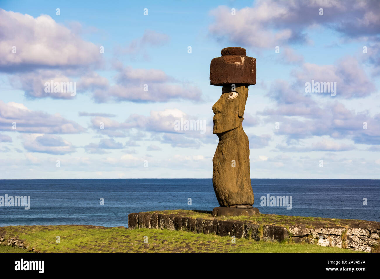 A single moai on a blue background of sky, clouds and ocean; Easter ...