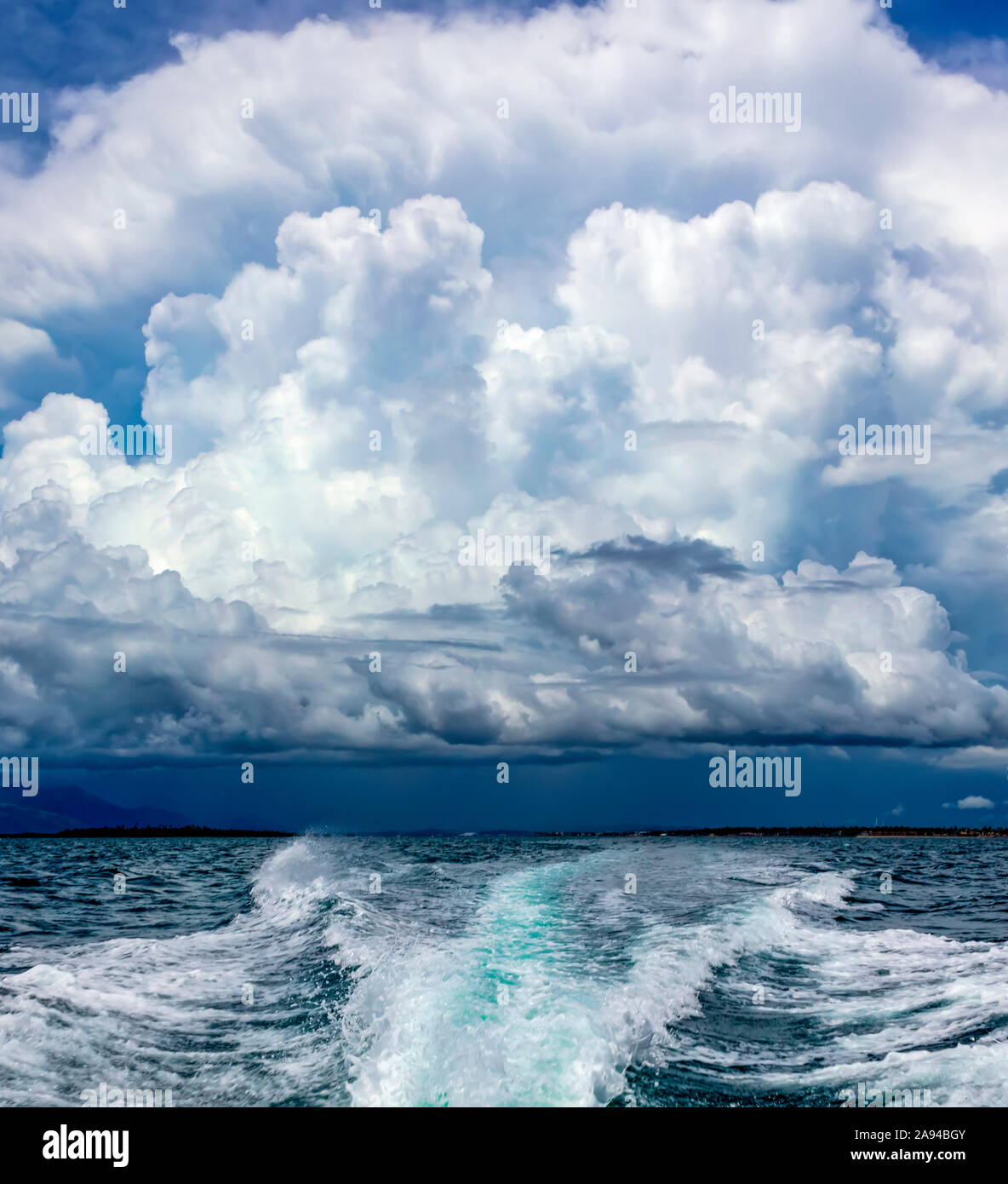 Wake from a boat in the ocean with dramatic storm clouds; Malolo Island ...
