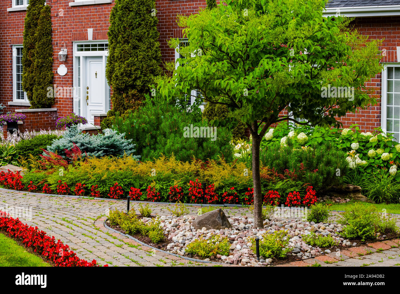 Stately brick house with a winding path and landscaping with plants and ...