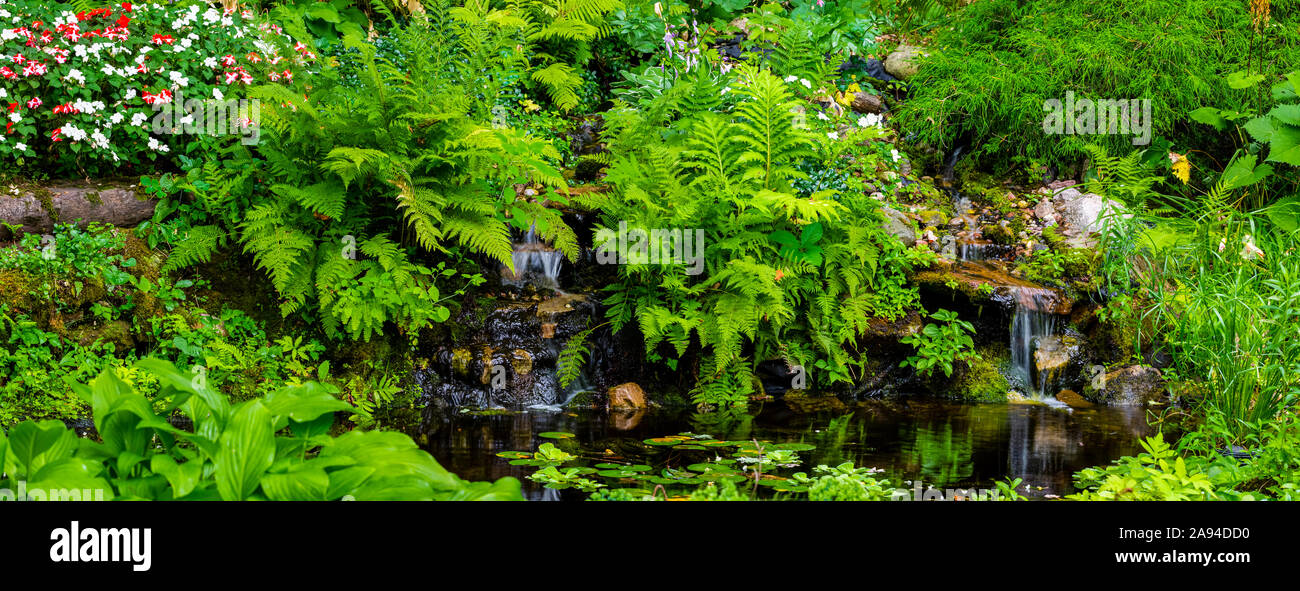 Landscaped flower garden in bloom with water feature; Hudson, Quebec ...