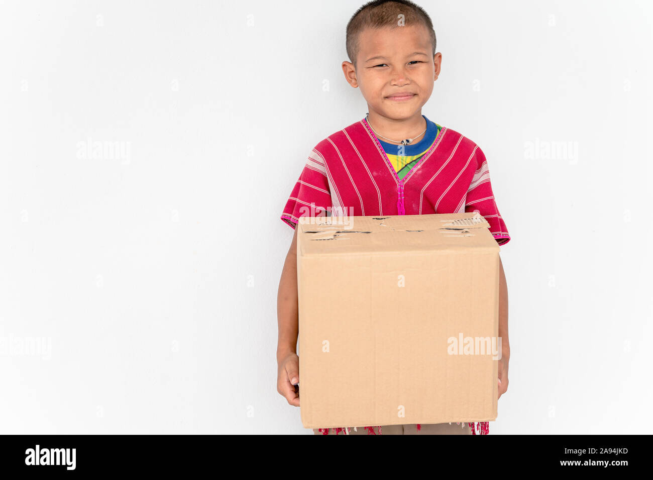 Young boy over isolated white background holding a box to move it to ...