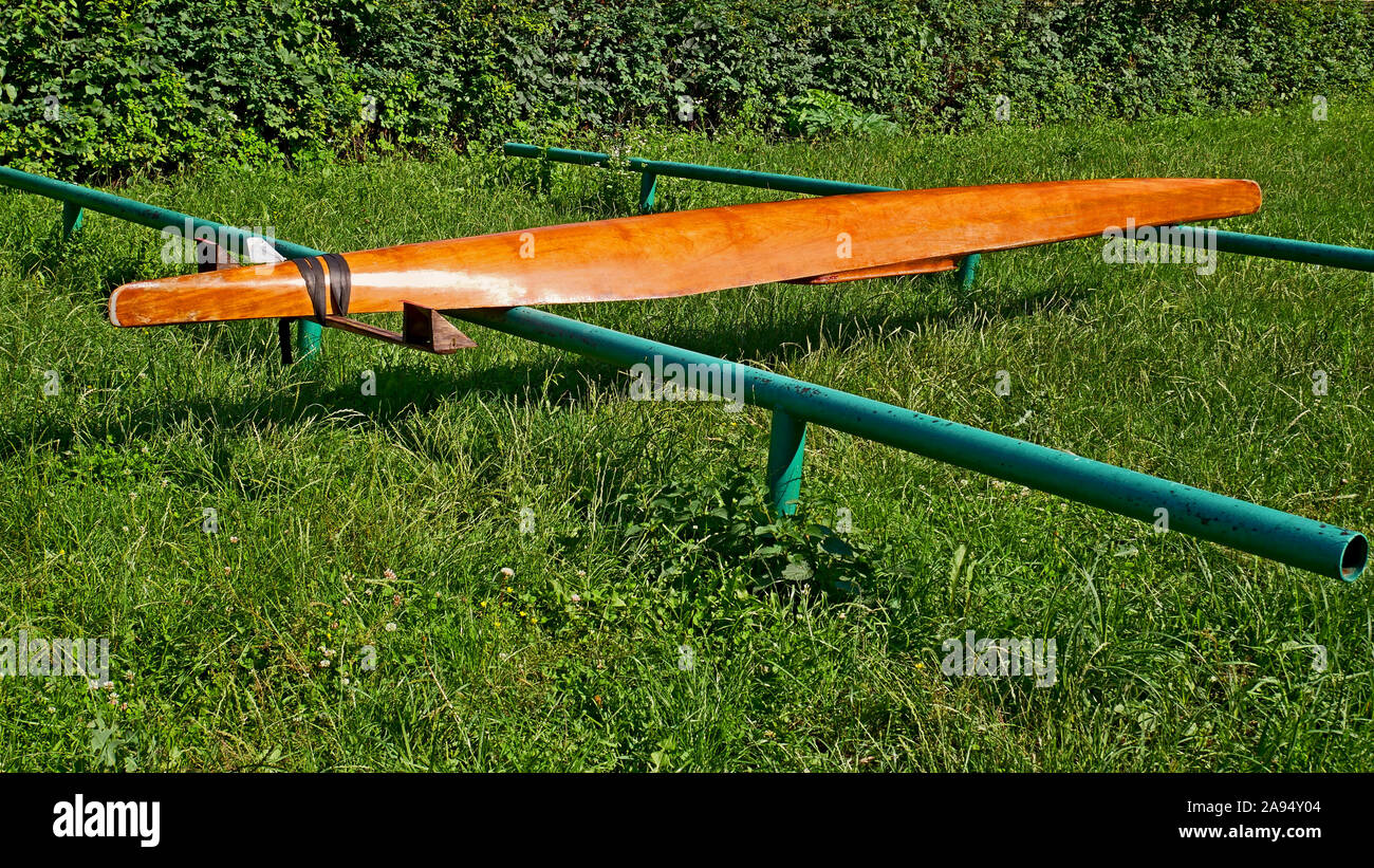 Parked wooden canoe inverted upside down to dry on a metal tubular ...