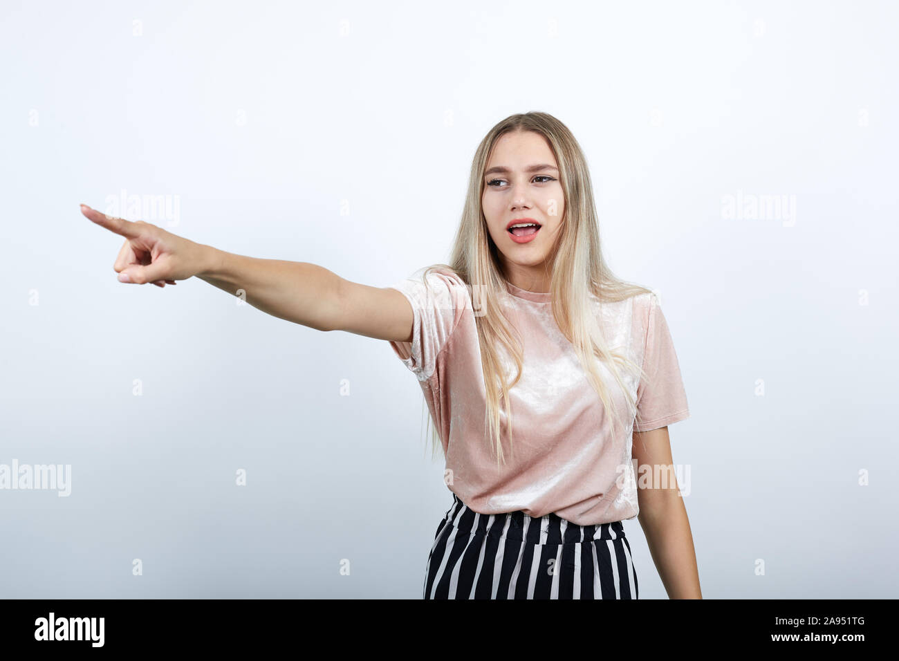 Beautiful blonde young lady staying pointing away his finger into ...