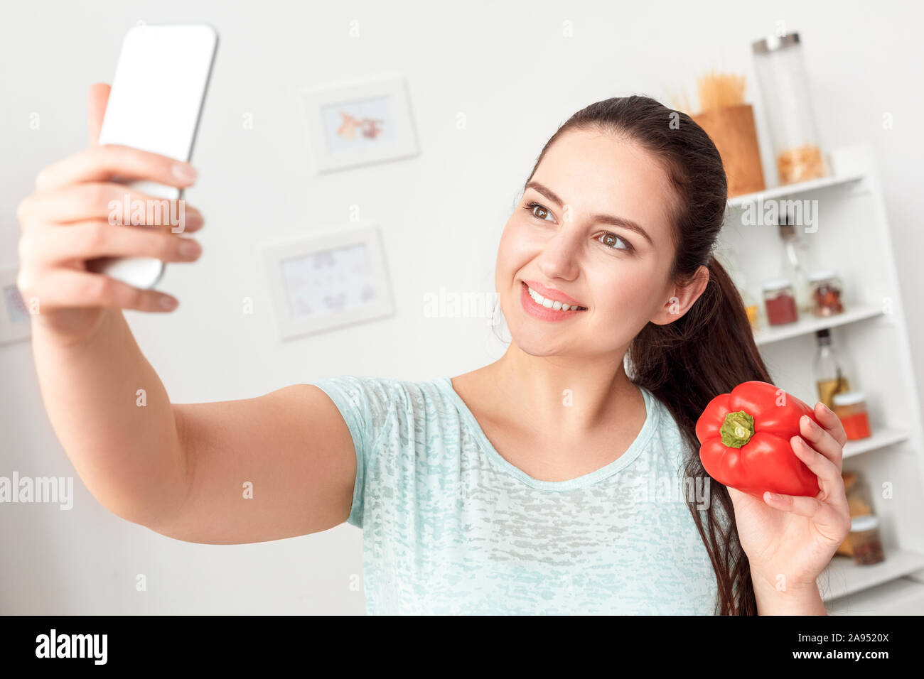 Body Care. Chubby girl standing in kitchen taking selfie on smartphone ...