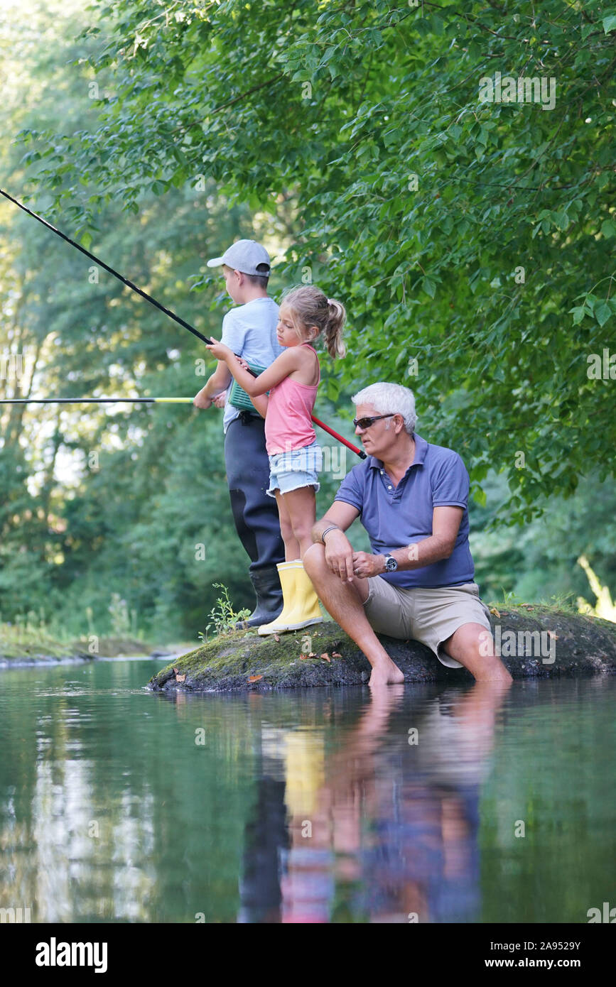 Dad teaching kids how to fish in river Stock Photo - Alamy