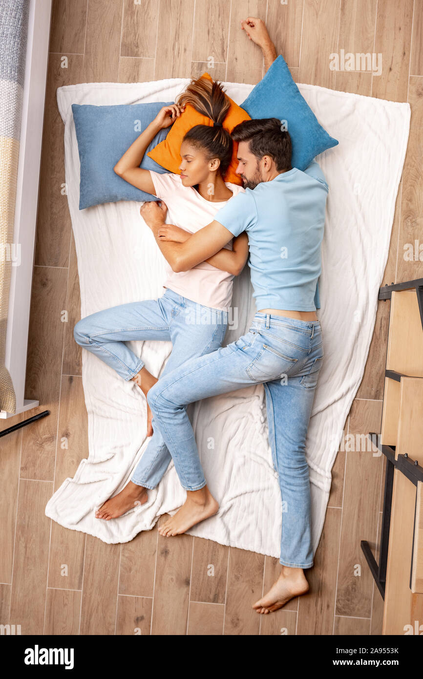 Mixed Race Couple. Young man and woman lying on bed top view hugging ...