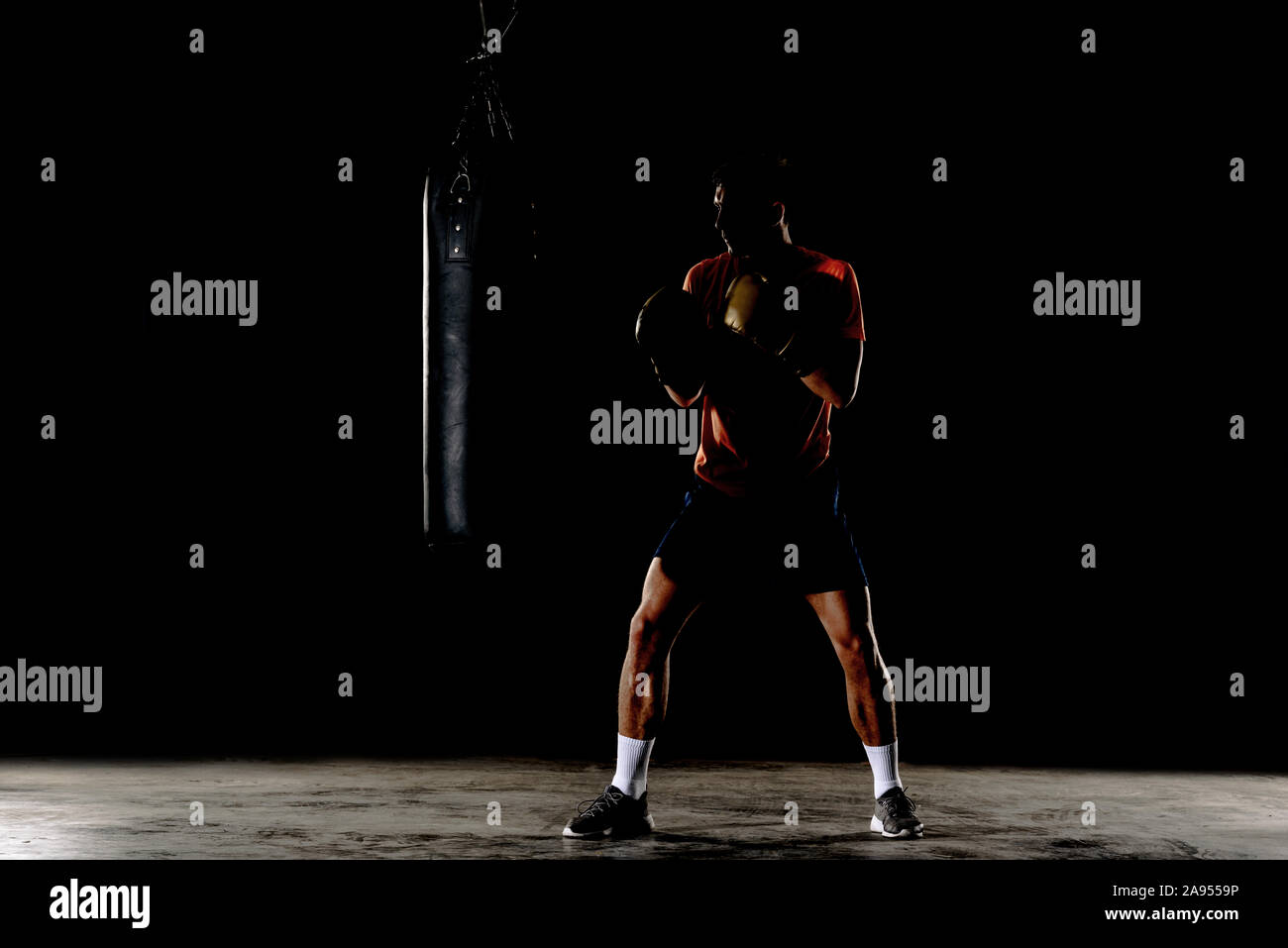 Silhouette male boxer hitting a huge punching bag at a boxing studio ...