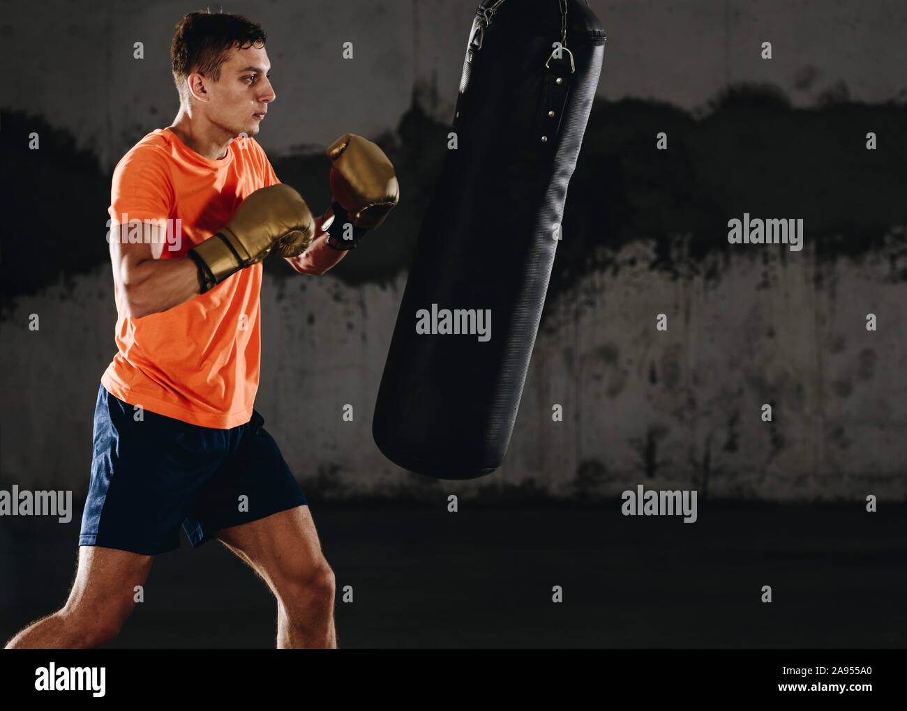 Silhouette male boxer hitting a huge punching bag at a boxing studio ...