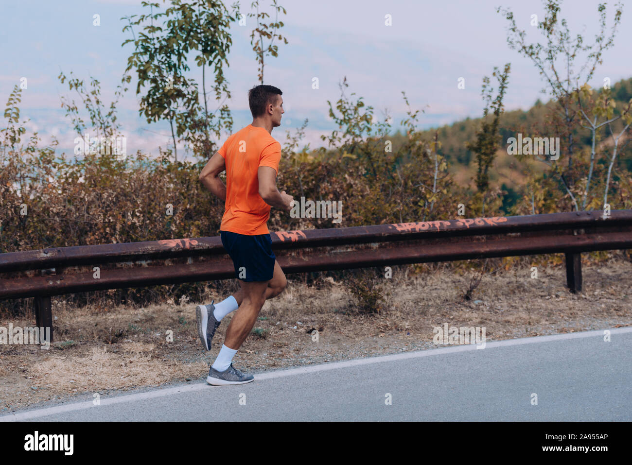 Sweaty man running on rural road. Hispanic male athlete training and ...