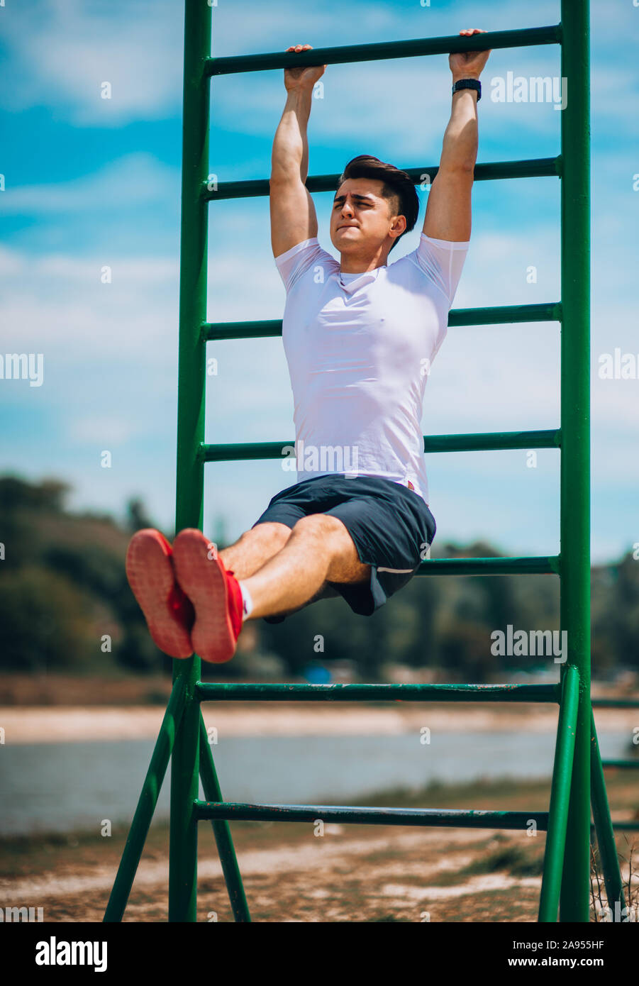 Sportsman with in black pants doing exersices on horizontal bar in a ...
