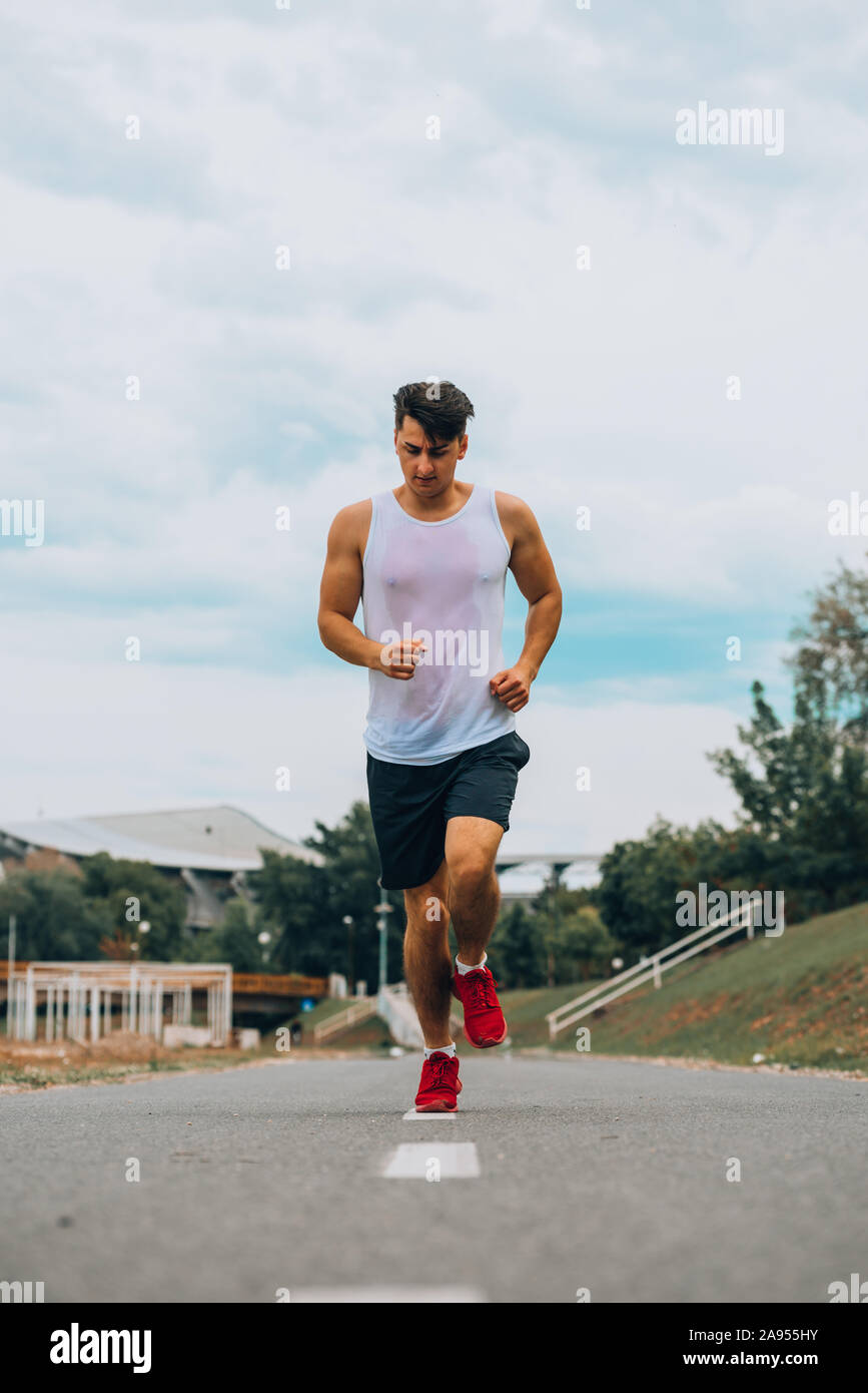 Low section image of young man running on country road in morning Stock ...