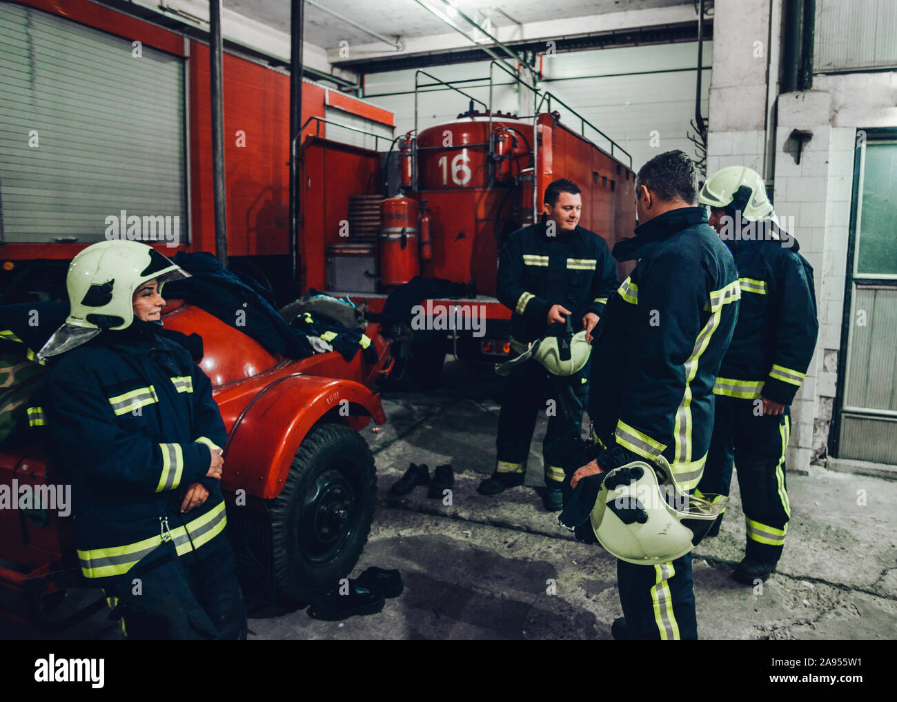 Portrait of confident firefighters with equipment against trucks at ...