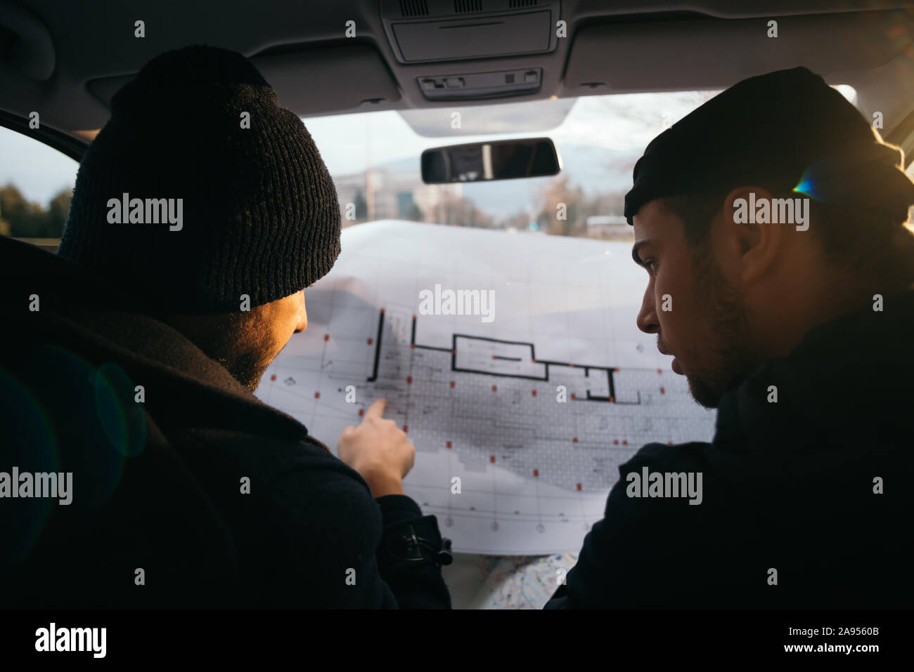 Two robbers planning and pointing on the blueprint(map) their objective ...
