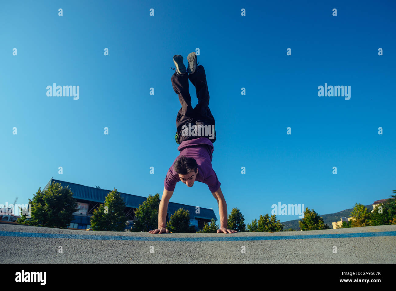 Acrobatic man balancing during a handstand on the concrete floor of the ...