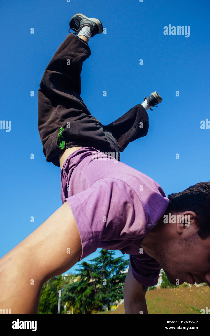 Acrobatic man balancing during a handstand on the concrete floor of the ...