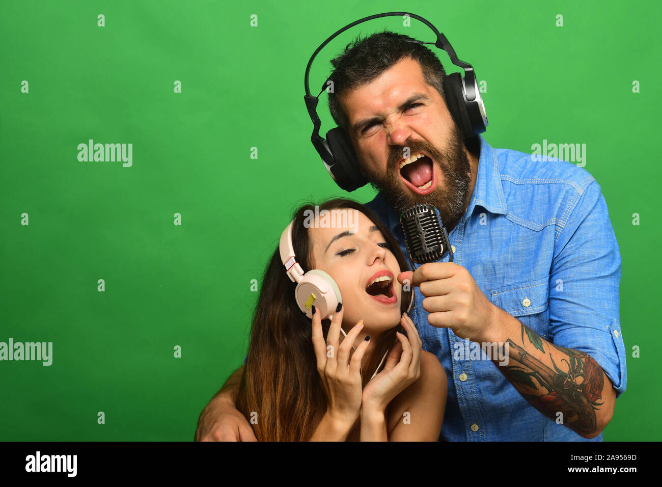 Couple in love holds microphone, sings on green background ...