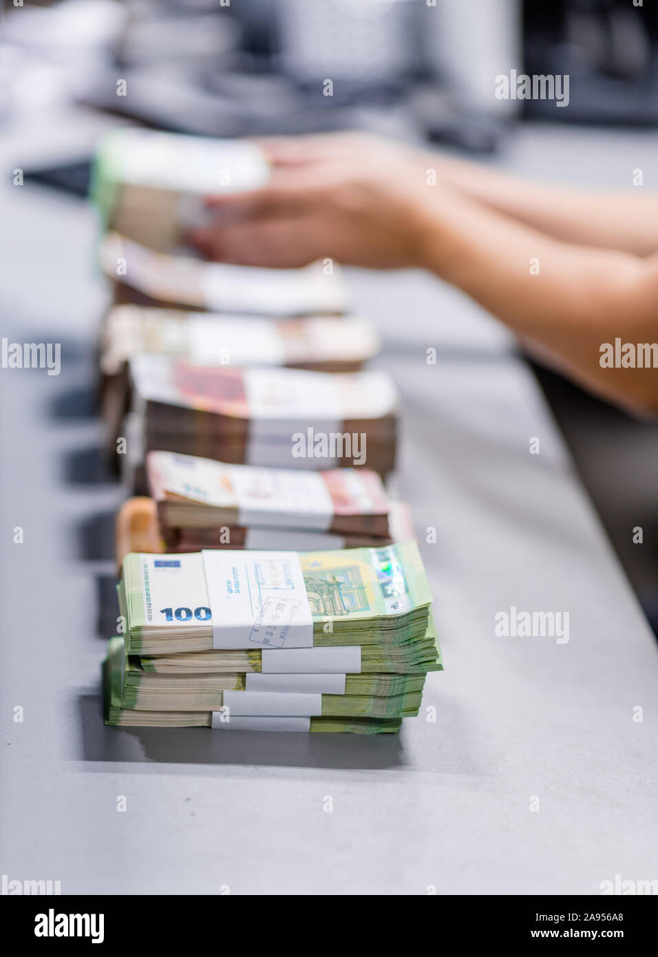 Office woman rearranging stacks of money divided with currency straps ...