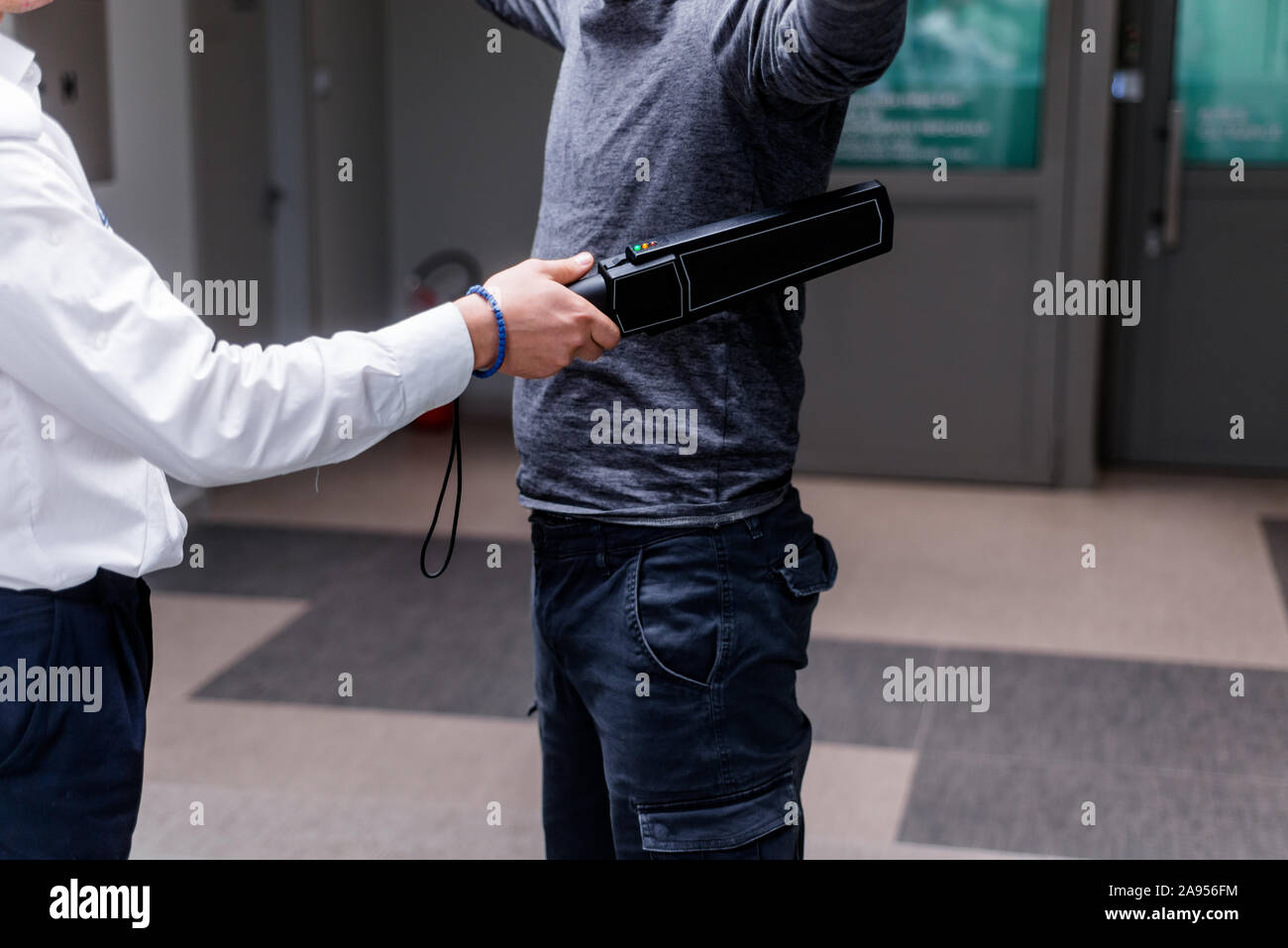 Guard with a metal detector checking a man for weapons and metal ...
