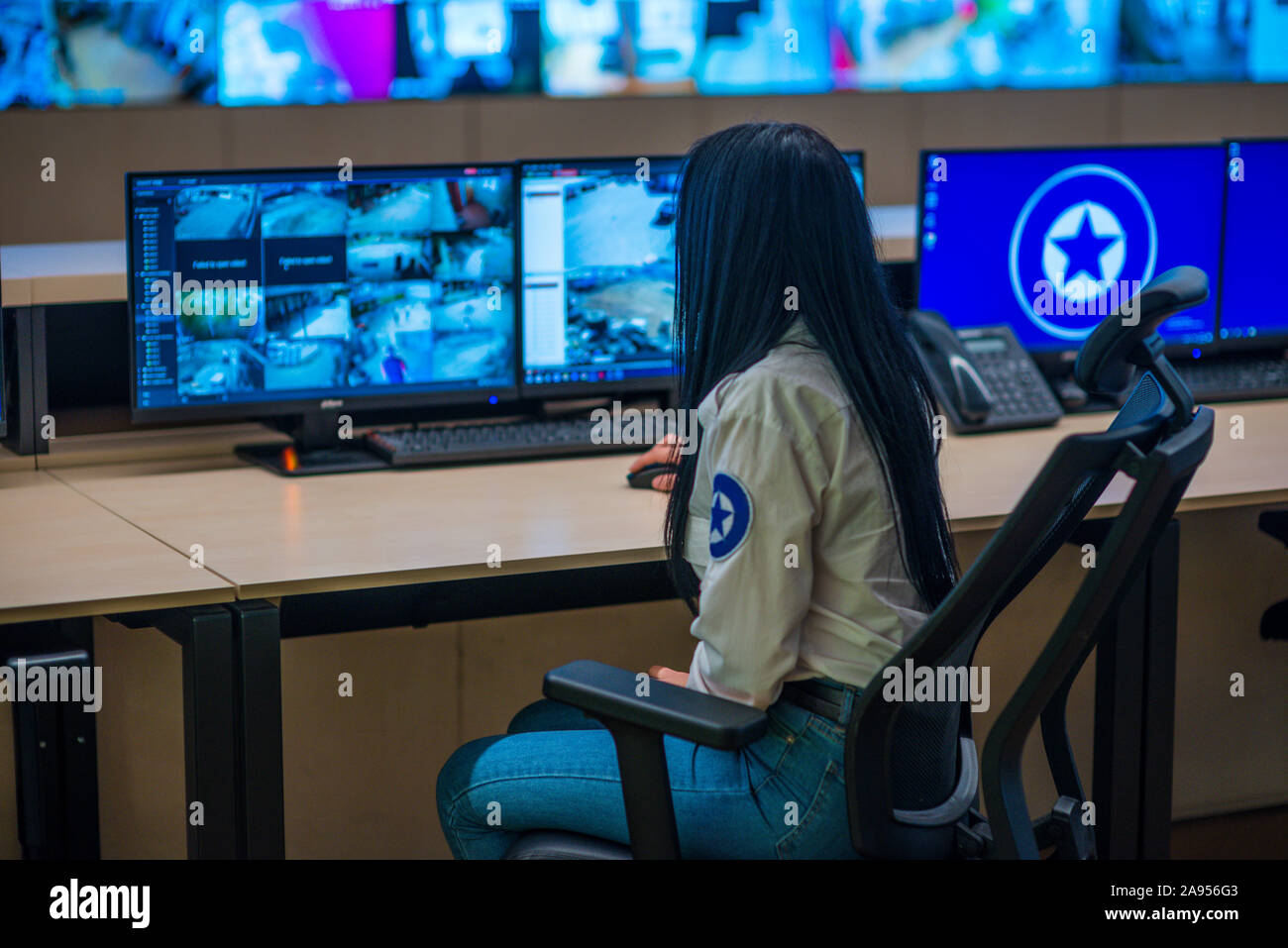 Female security guard sitting back and monitoring modern CCTV cameras ...