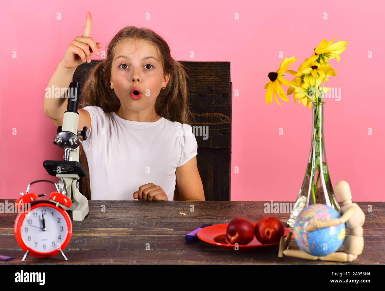 Girl with enthusiastic face has good idea. Schoolgirl at her desk with ...
