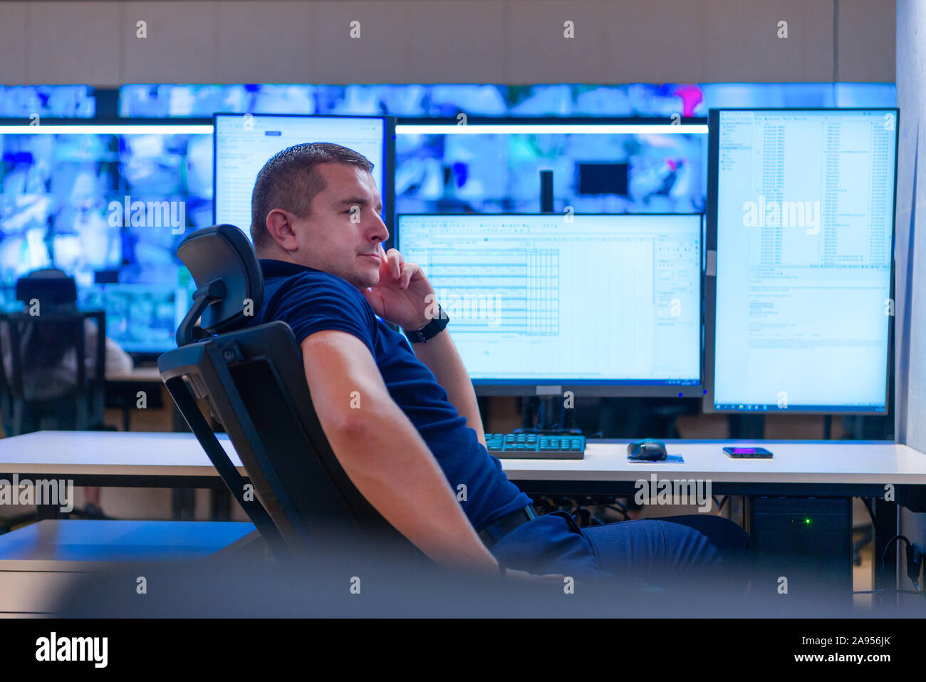 Side view of security system operator using walkie-talkie while looking ...