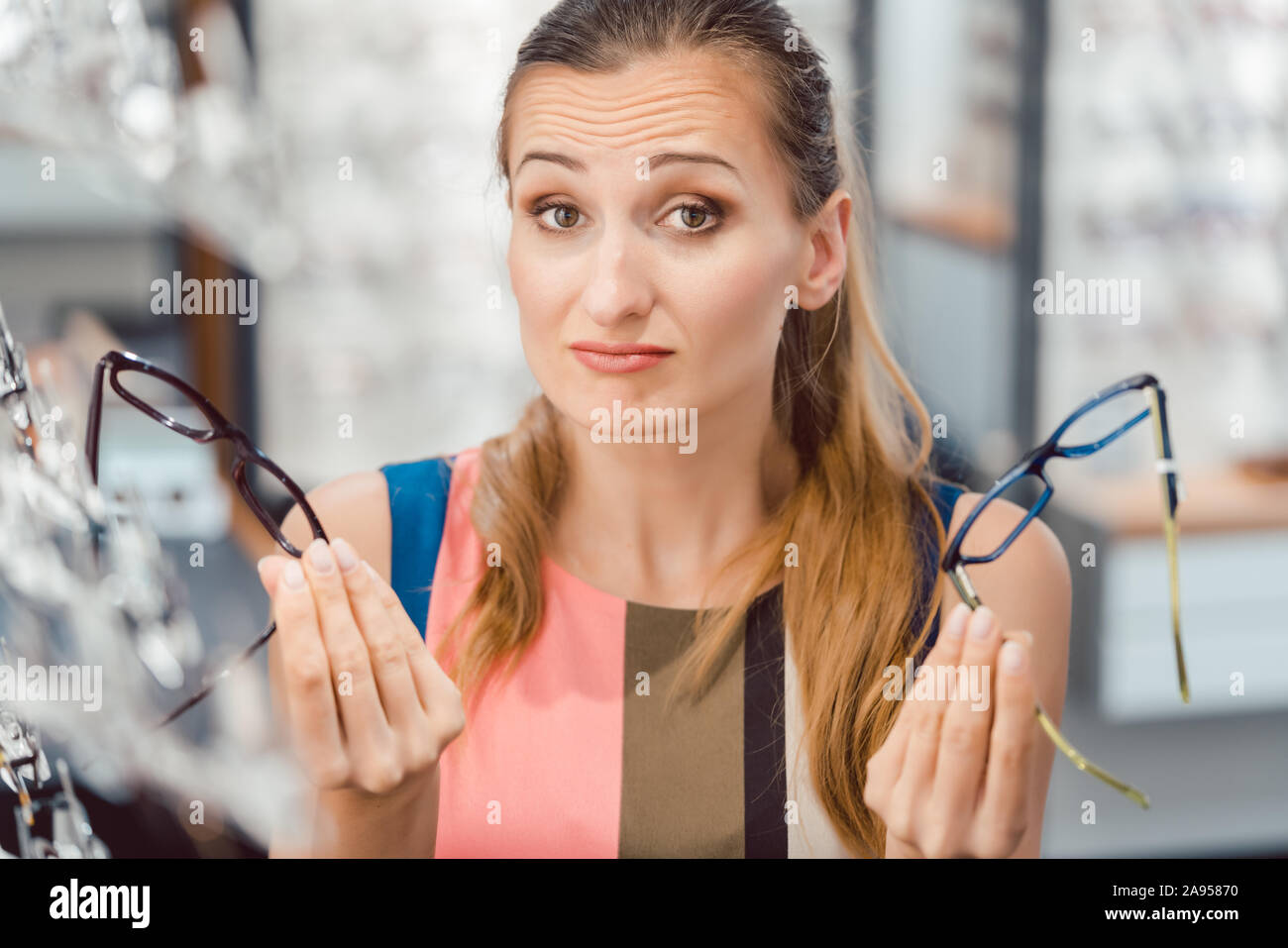 Woman choosing between two models of glasses at optometrist Stock Photo ...