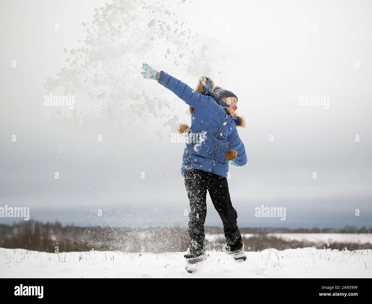 Happy child jumping. Lots of flying snow. Enjoy outdoor games in winter ...